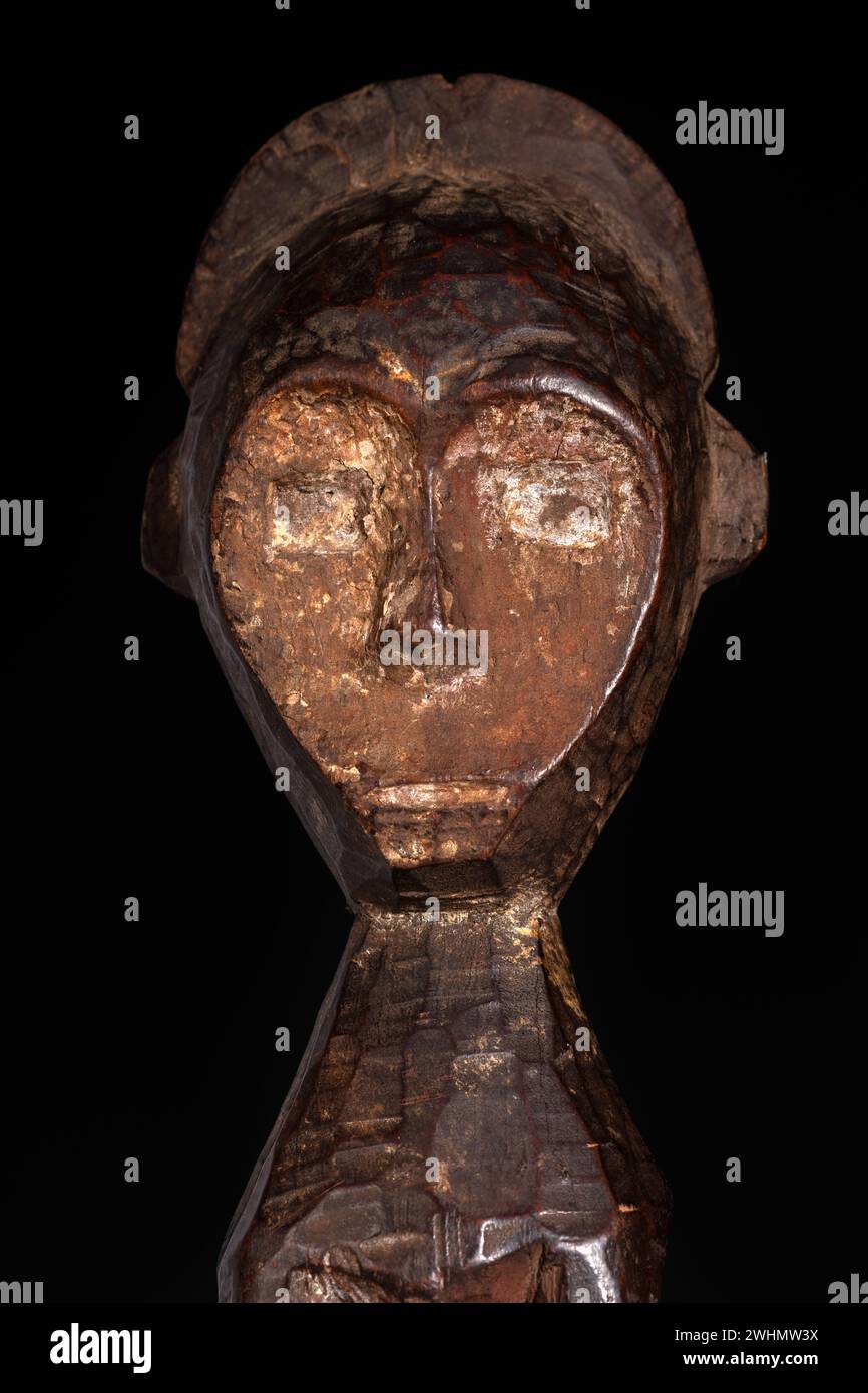 An African male figure portrait carved in wood isolated on black ...