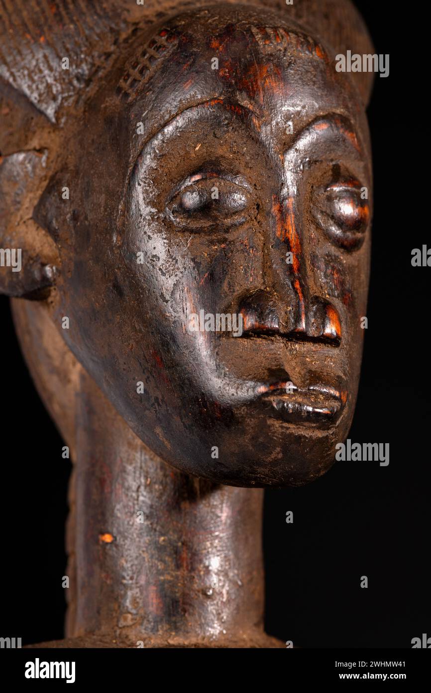 An African female statue carved in wood isolated on black. Traditional ...