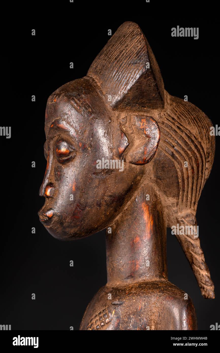 An African female statue carved in wood isolated on black. Traditional ...