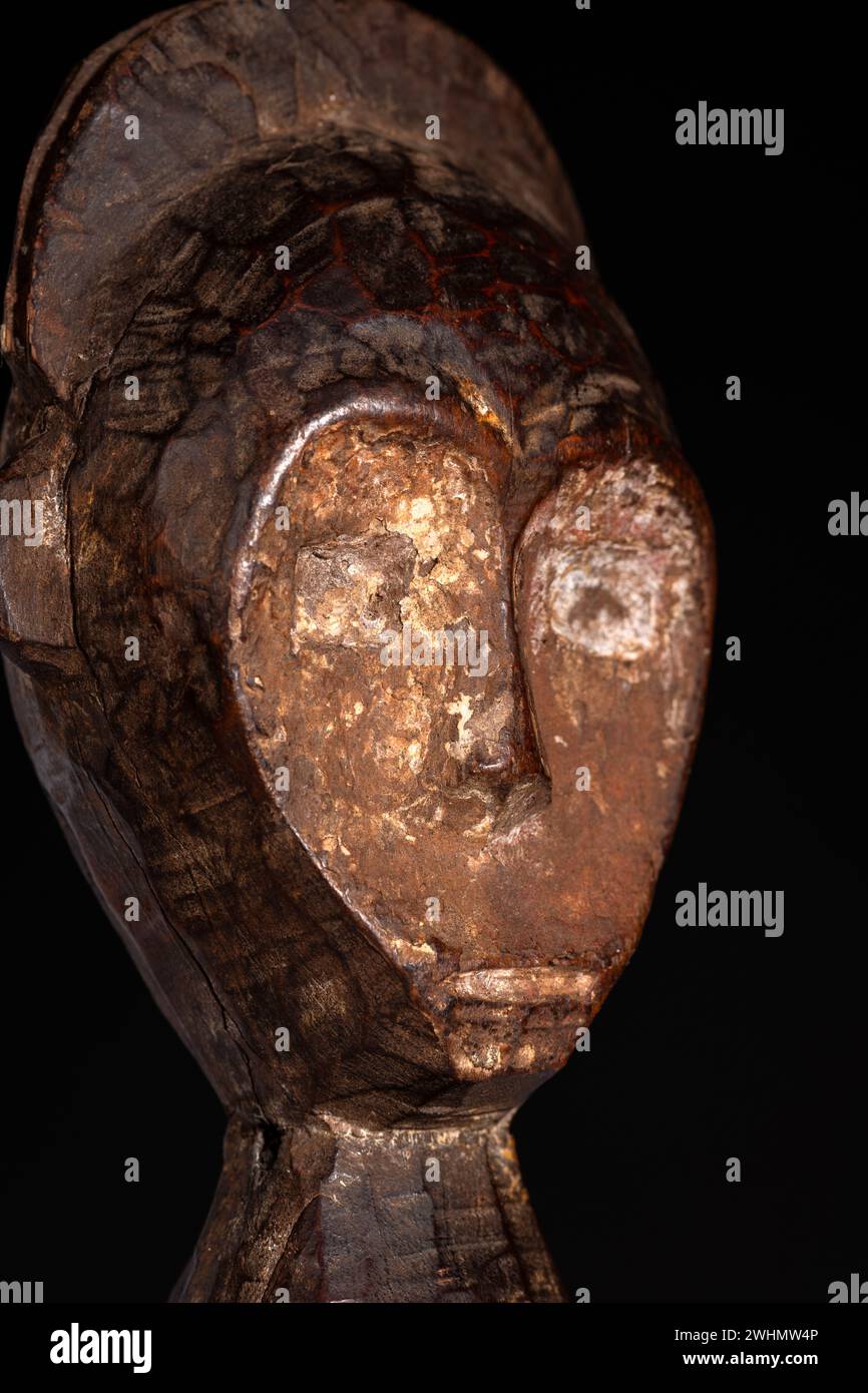 An African male figure portrait carved in wood isolated on black ...