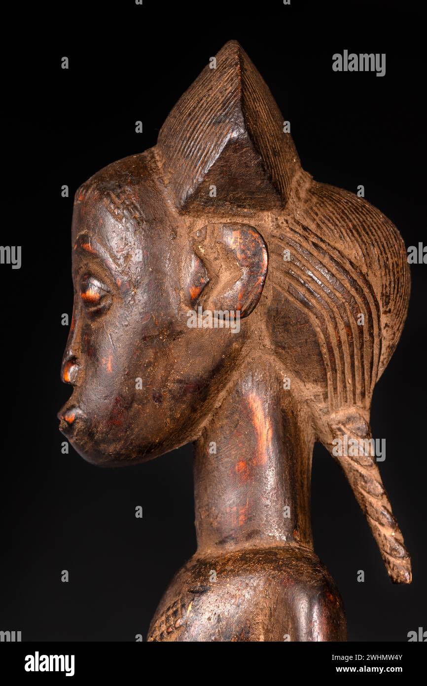 An African female statue carved in wood isolated on black. Traditional ...