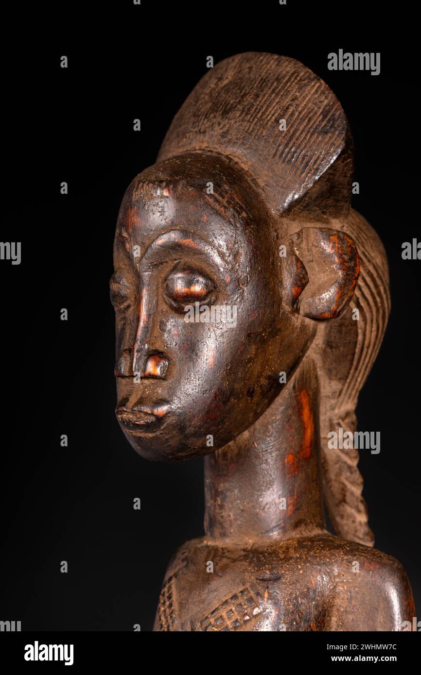 An African female statue carved in wood isolated on black. Traditional ...