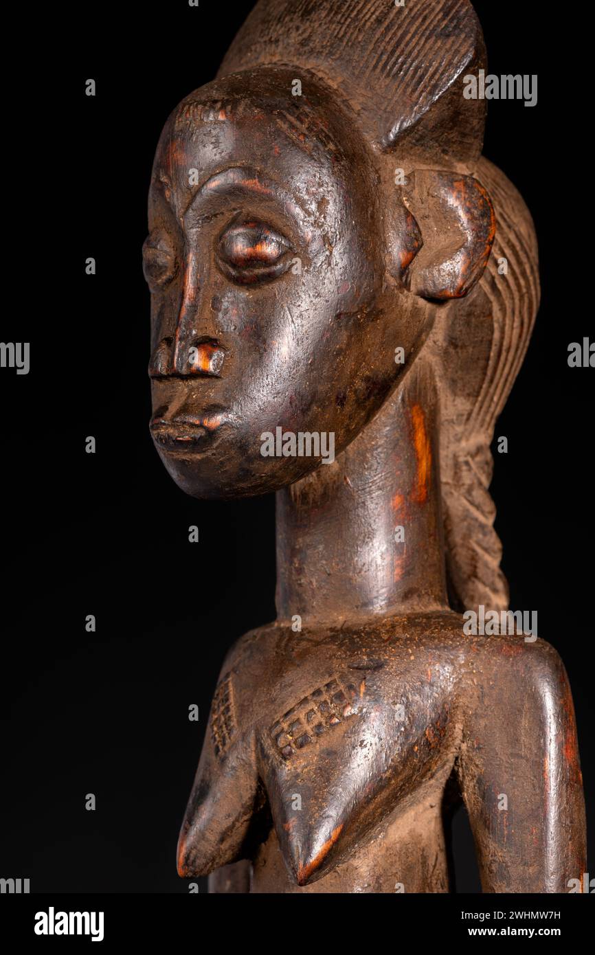 An African female statue carved in wood isolated on black. Traditional ...