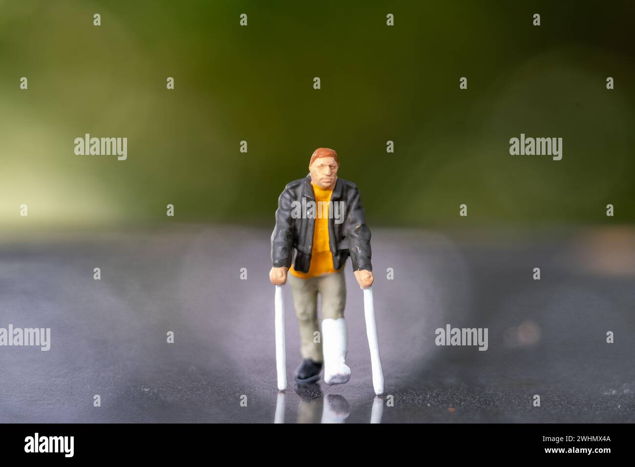 Miniature people man with broken leg is using crutch For Walking Stock ...