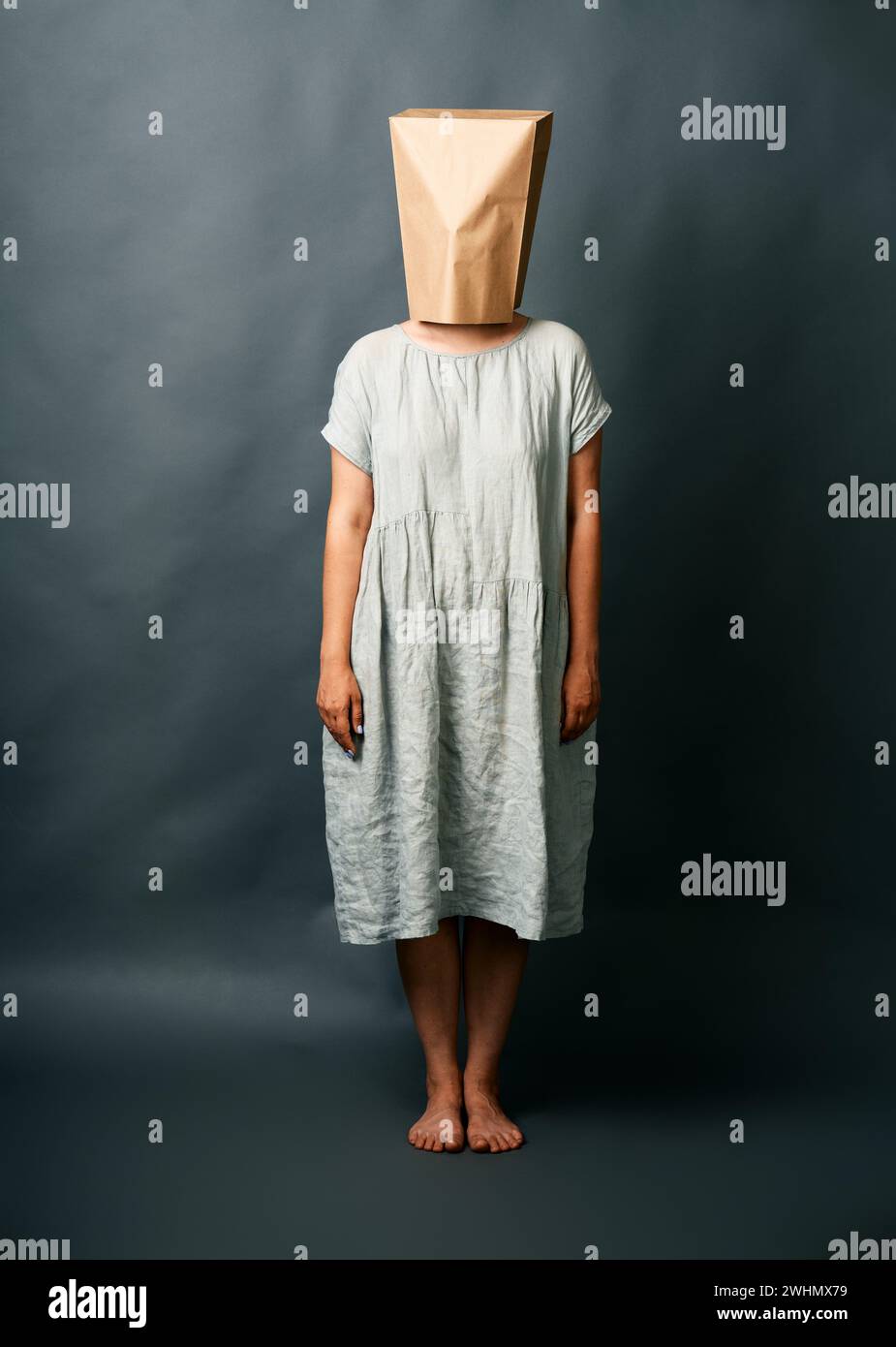Full length portrait of woman in long dress hiding under empty paper ...