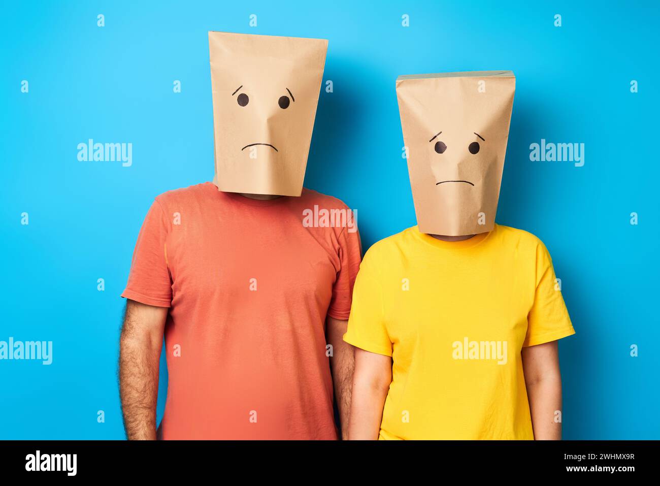 Unhappy couple with bags over heads over blue studio background Stock ...