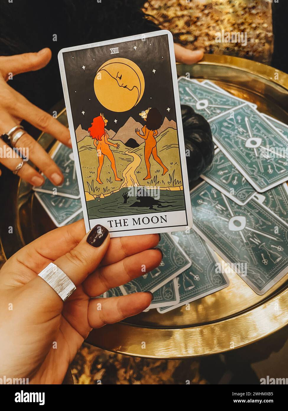 Young women make a layout of tarot cards. A girl with a black manicure ...