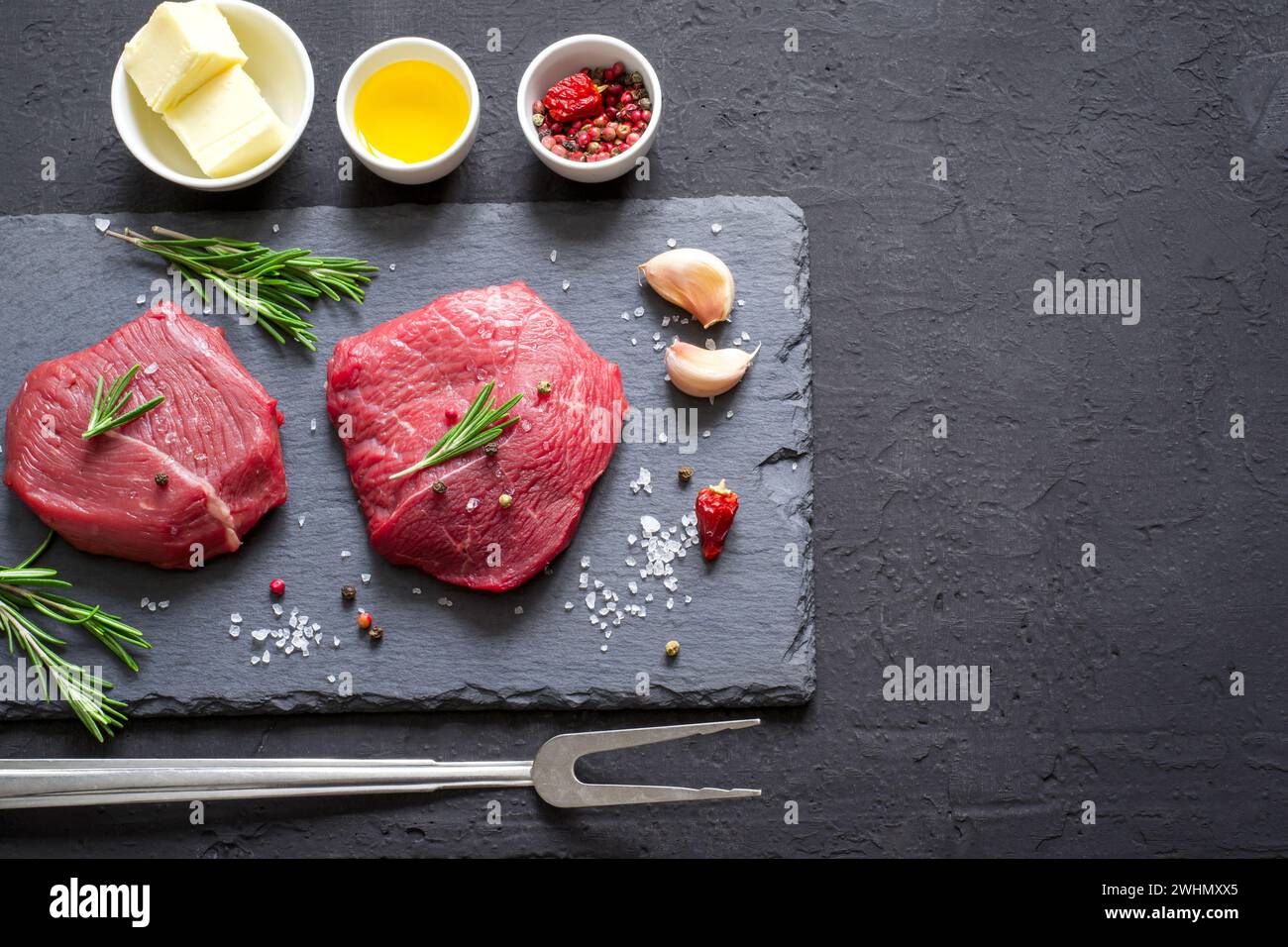 Raw meat beef steaks on black slate board, spices and ingredient Stock ...