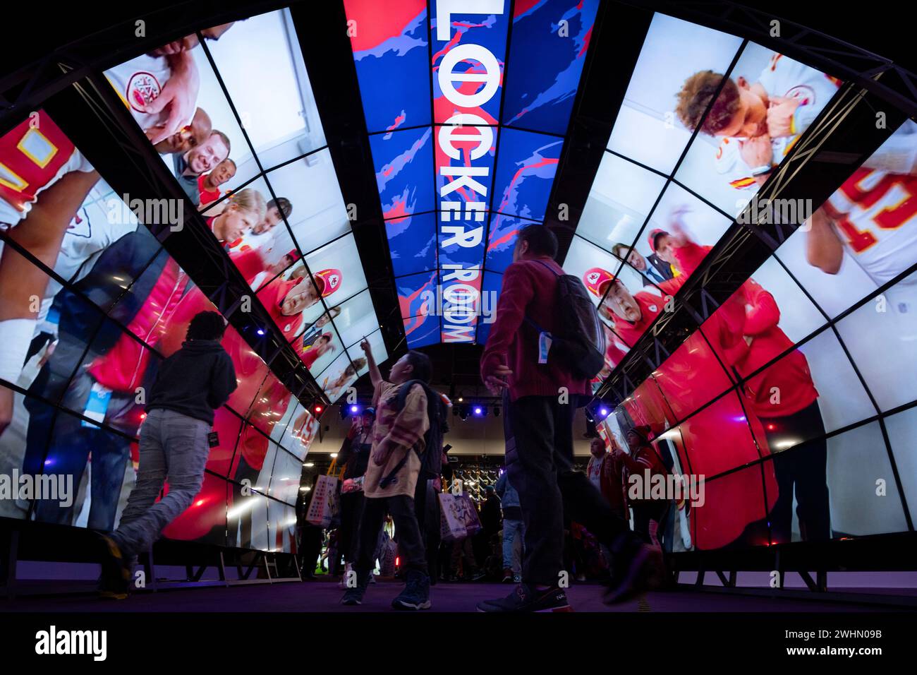 People walk through a tunnel of screens showing scenes from NFL ...