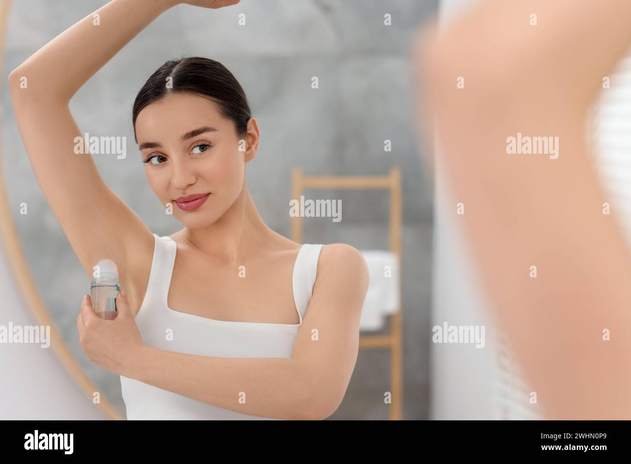 Beautiful woman applying deodorant near mirror in bathroom Stock Photo ...