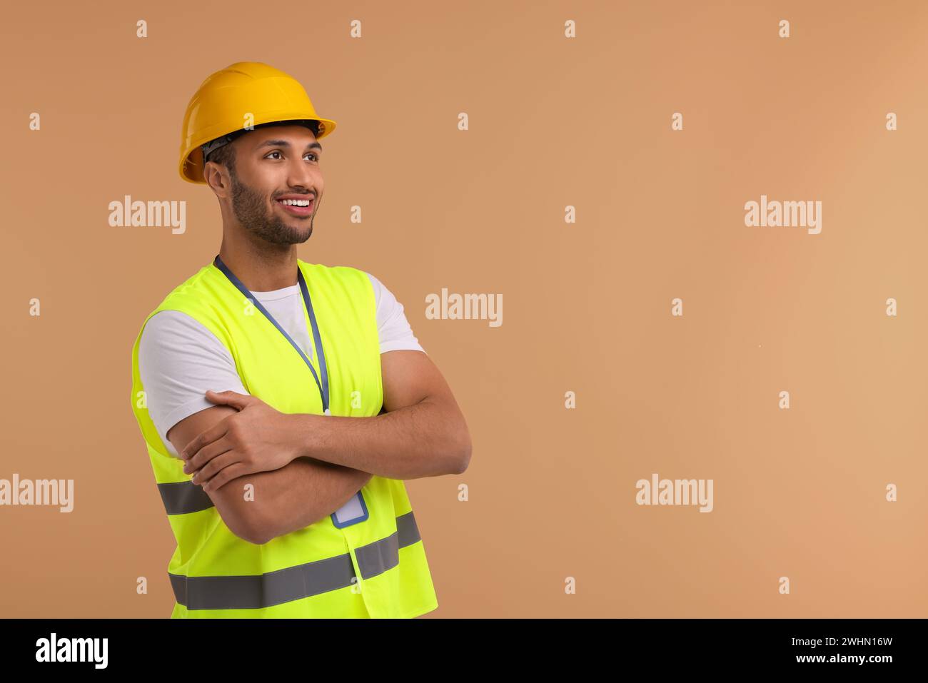 Engineer with hard hat and badge on beige background, space for text ...
