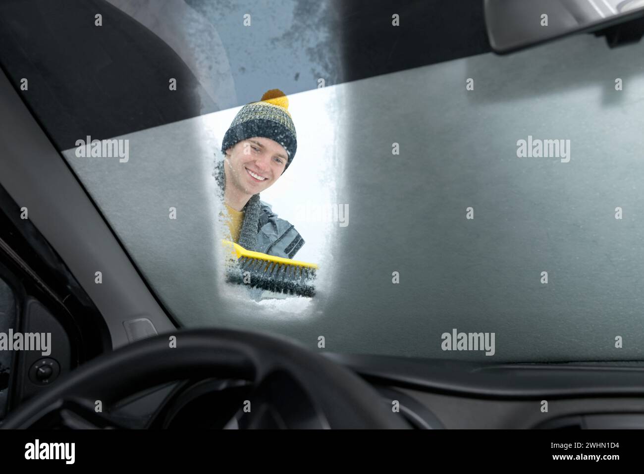 Man cleaning snow from car windshield, view from inside Stock Photo - Alamy