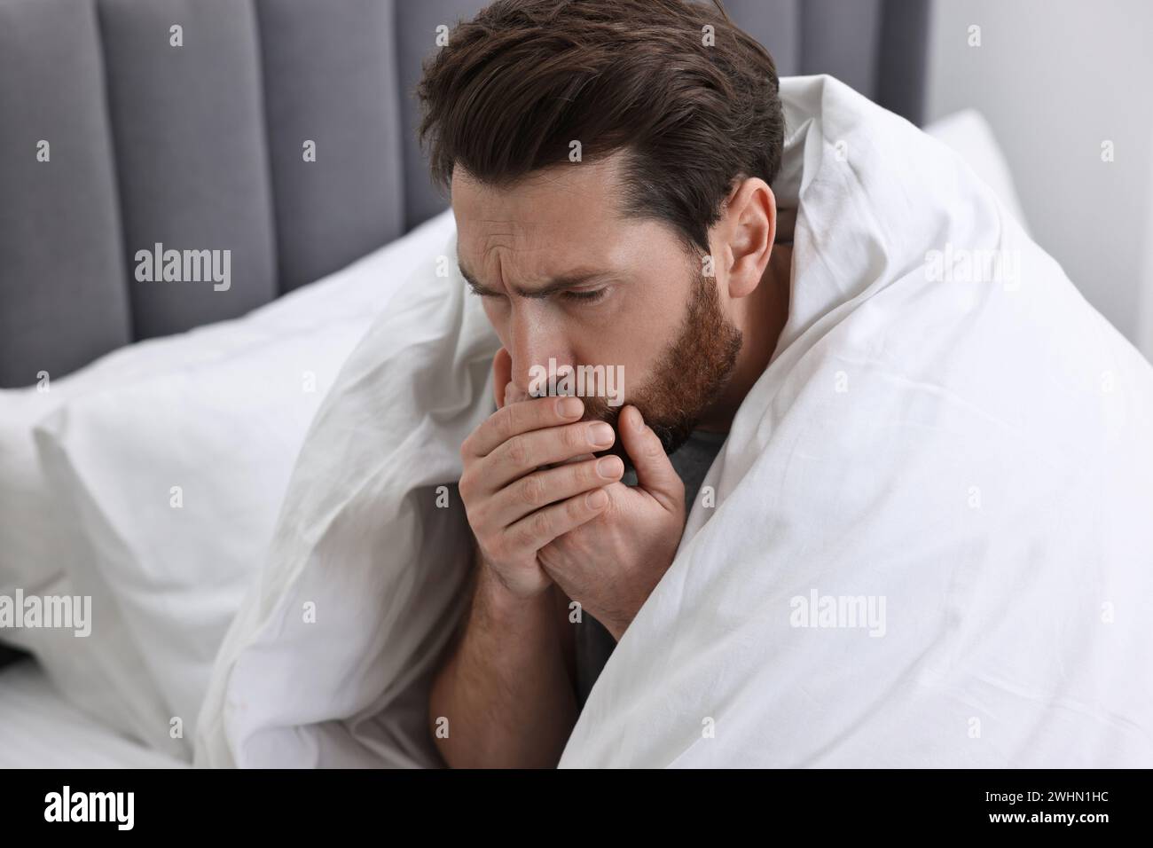 Sick man coughing on bed. Cold symptoms Stock Photo - Alamy