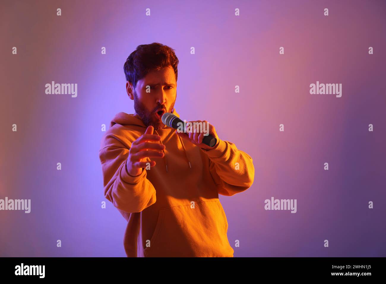 Singer with microphone rapping in color lights Stock Photo - Alamy