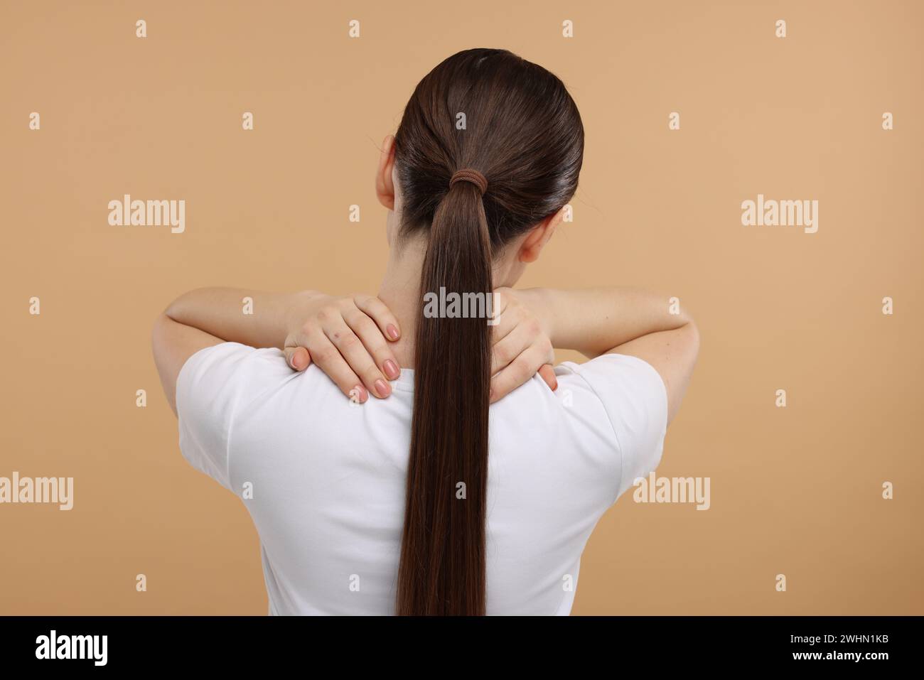 Woman touching her neck on beige background, back view Stock Photo - Alamy