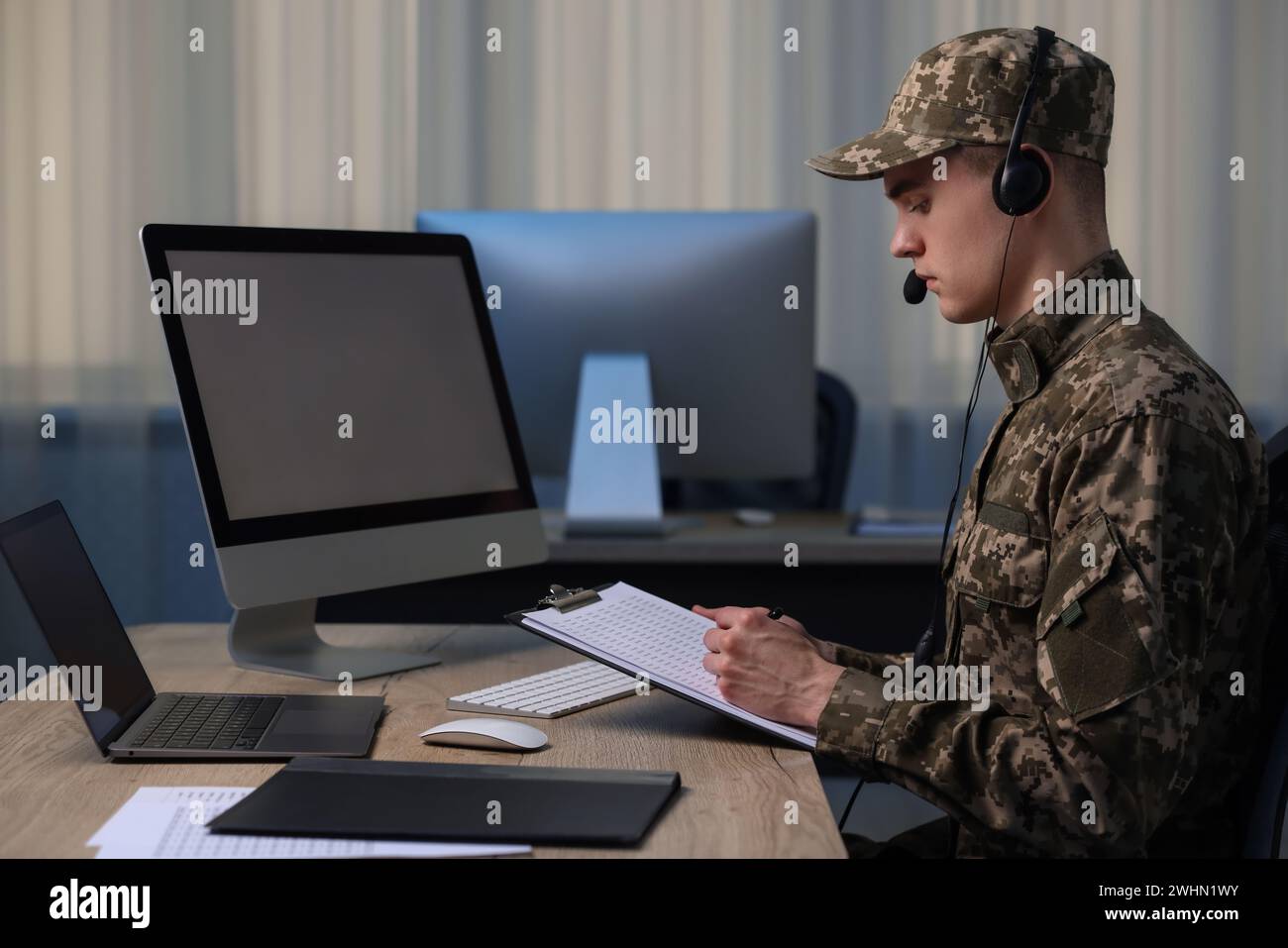 Military service. Young soldier with clipboard and headphones working ...