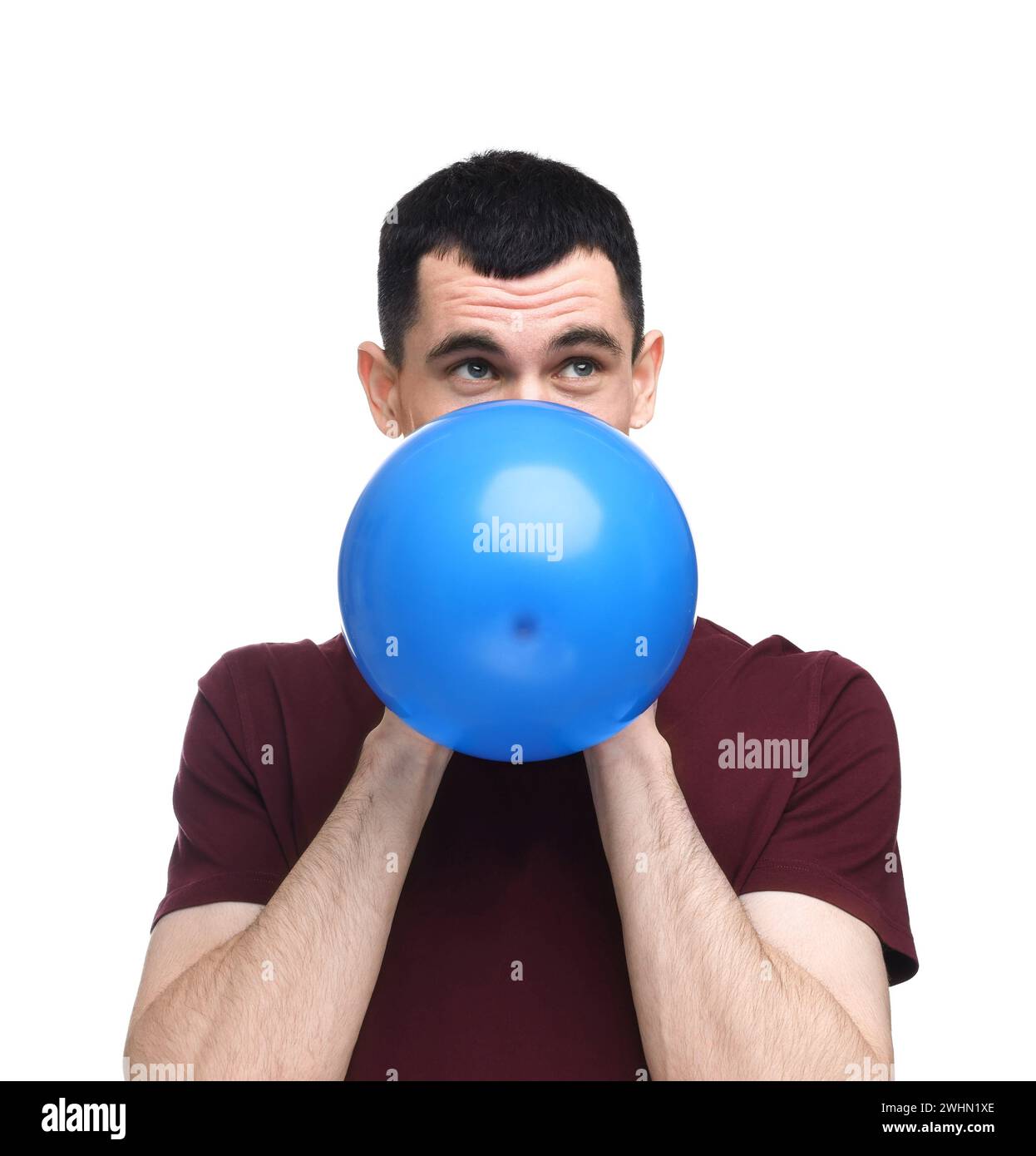 Young man inflating light blue balloon on white background Stock Photo ...