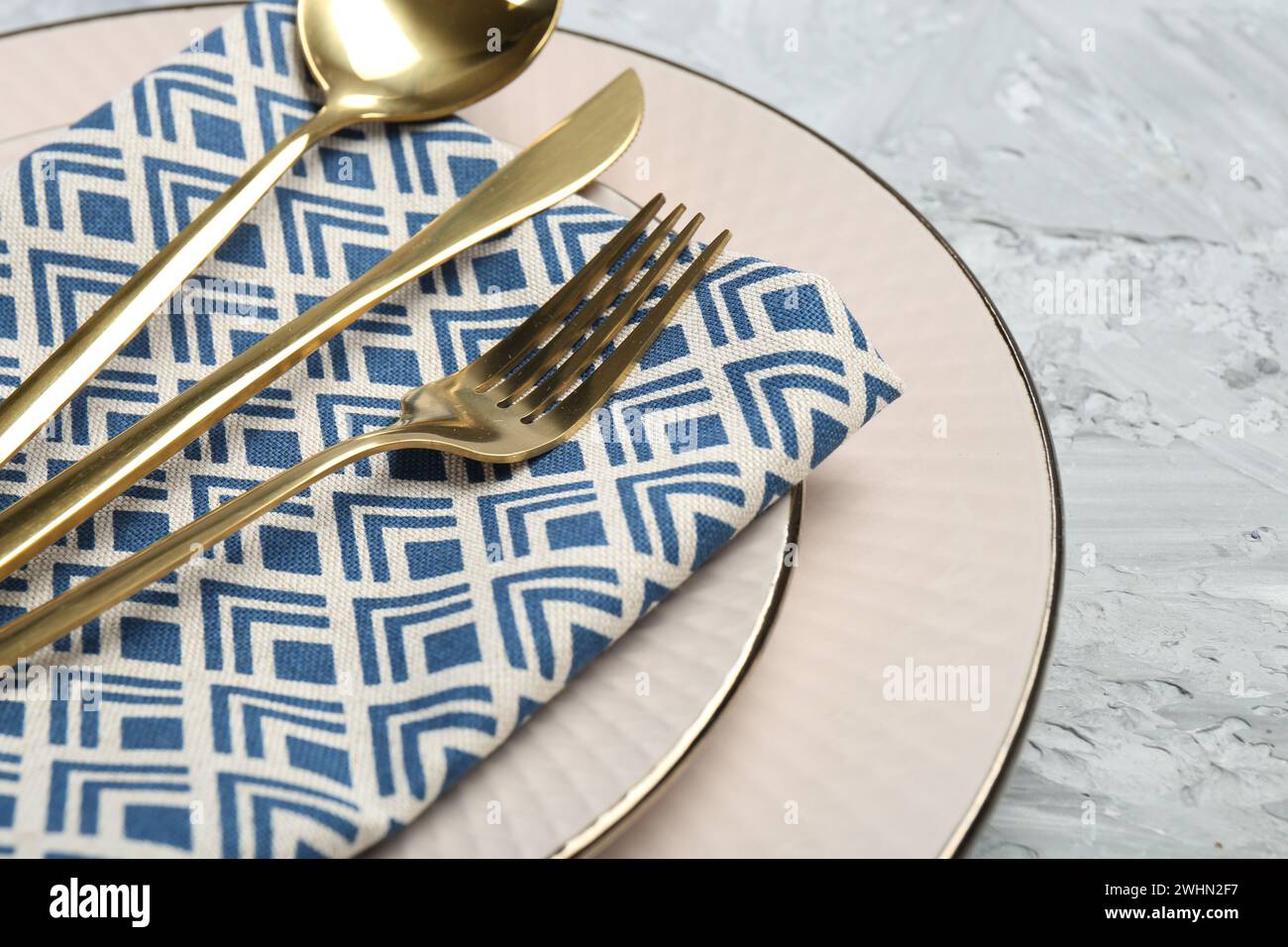 Clean plates, cutlery and napkin on light grey textured table, closeup ...