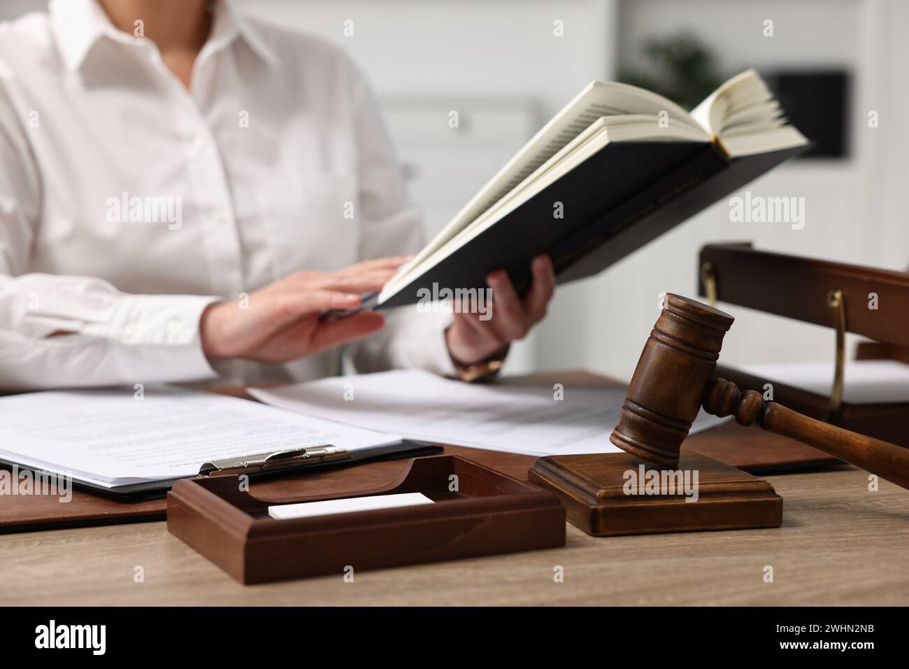 Lawyer working with documents at wooden table in office, focus on gavel ...