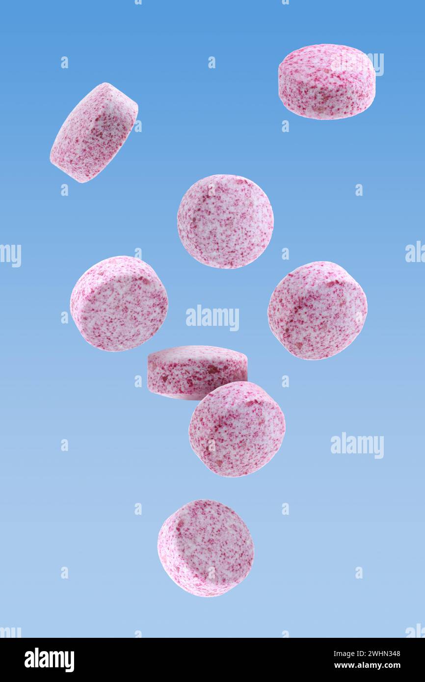 Vitamin. Pink tablets falling on light blue gradient background Stock ...