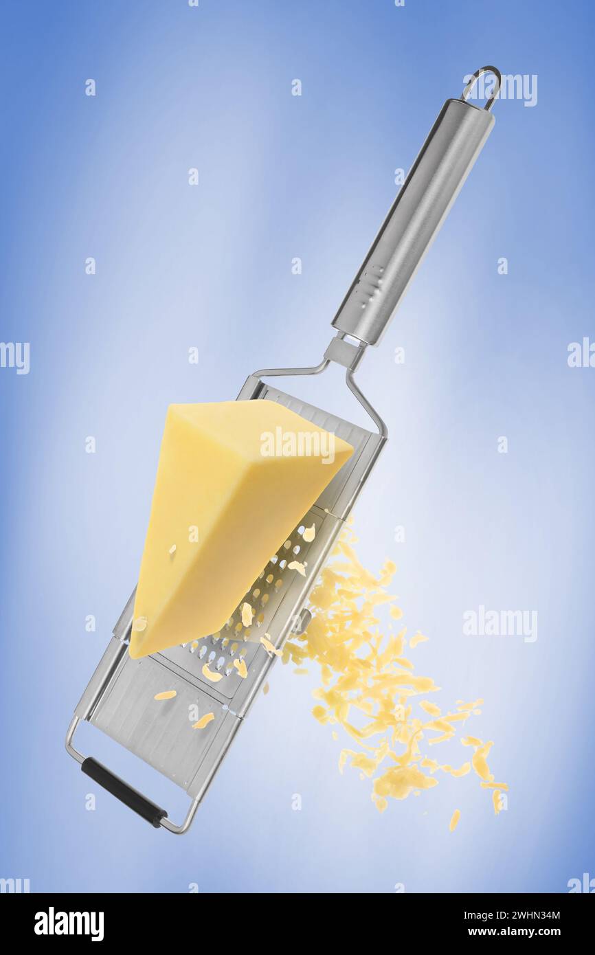 Grating cheese with hand grater on blue background Stock Photo - Alamy