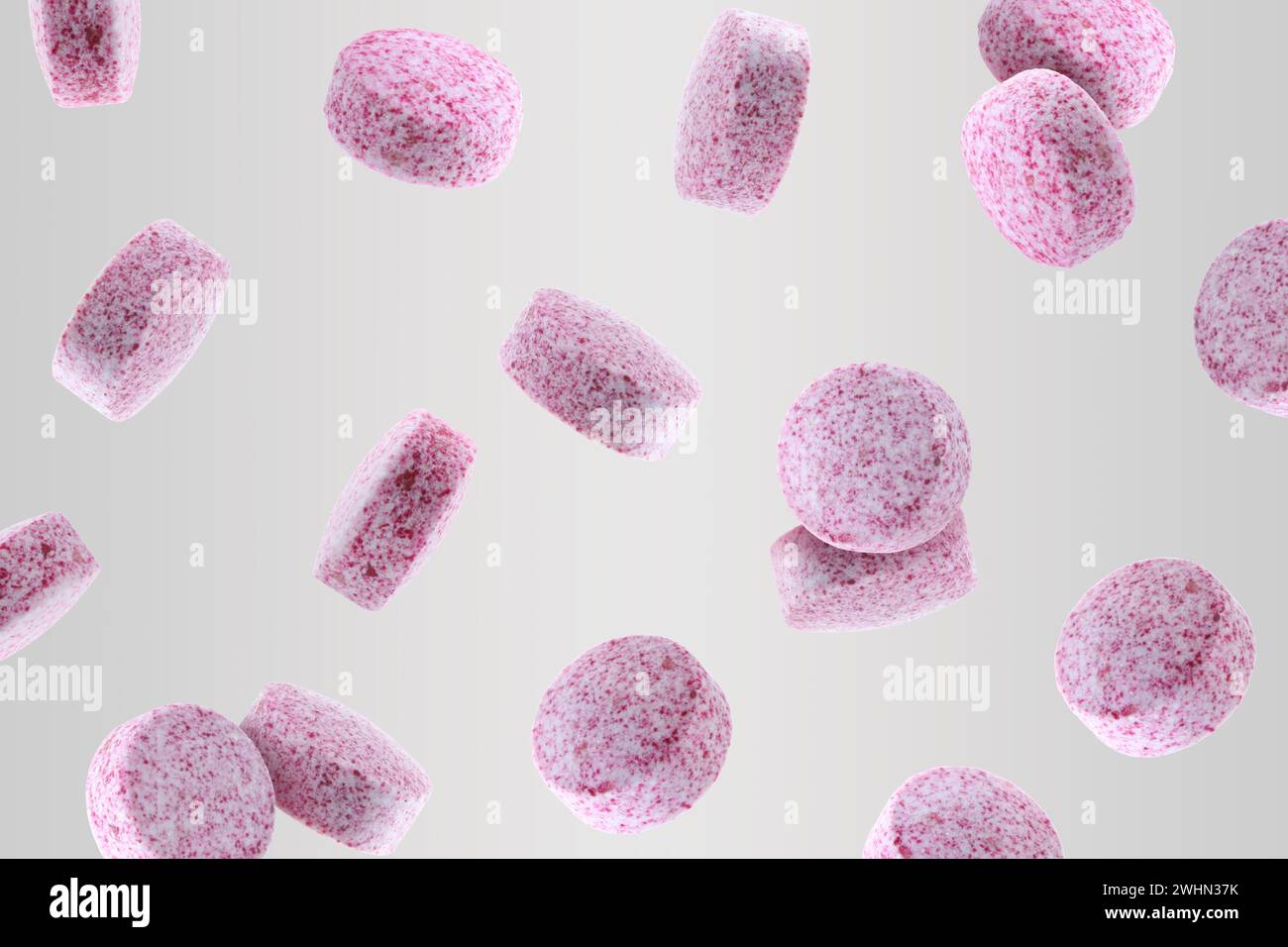 Vitamin. Pink tablets falling on light grey background Stock Photo - Alamy
