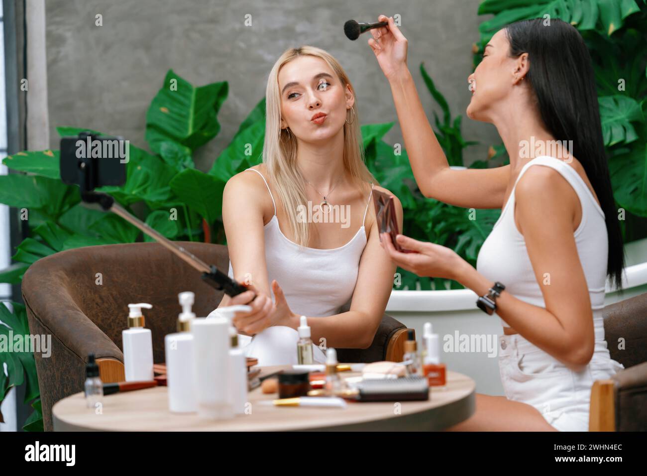 Two beautiful content creator making natural beauty and cosmetic tutorial on green plant garden ...