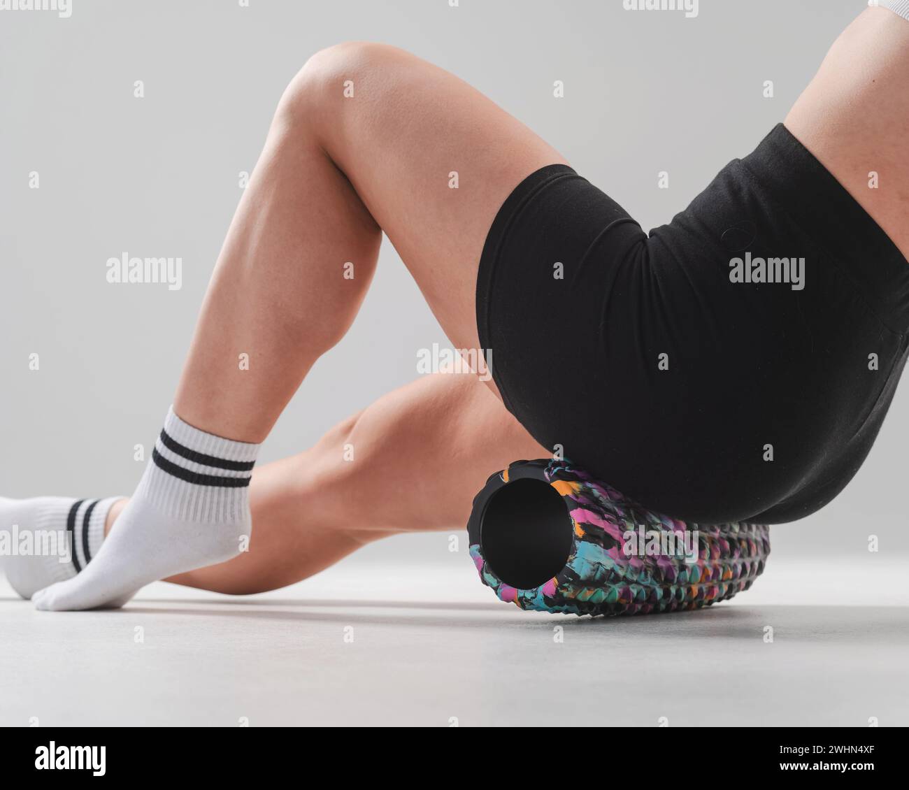 Faceless woman doing roller exercise for myofascial release on white ...