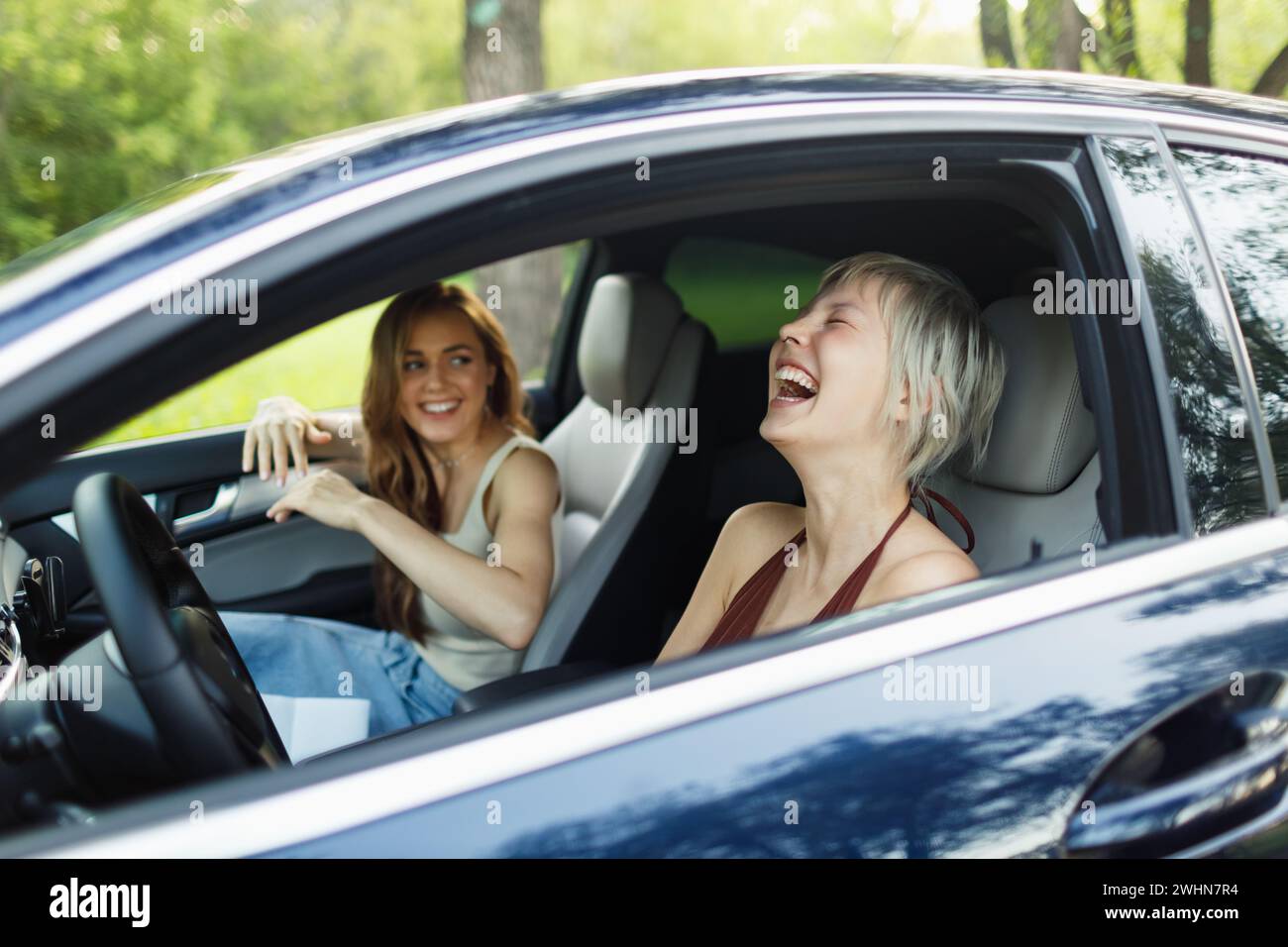 Two woman drivers at car smiling. Cute young happy female driving car ...