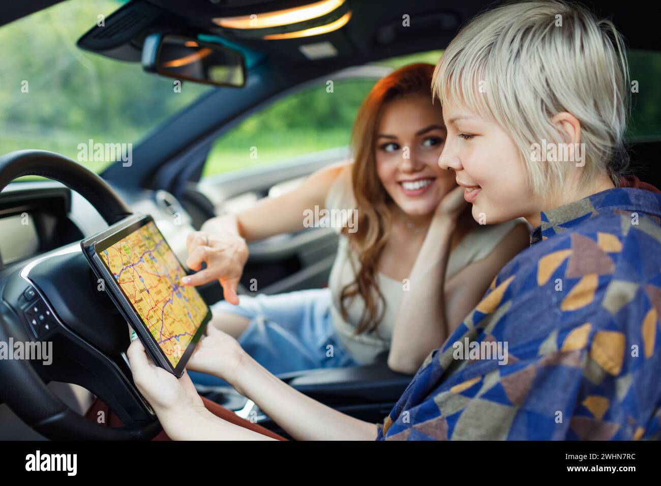 Happy young two women driver tourist travelers with digital tablet USA ...