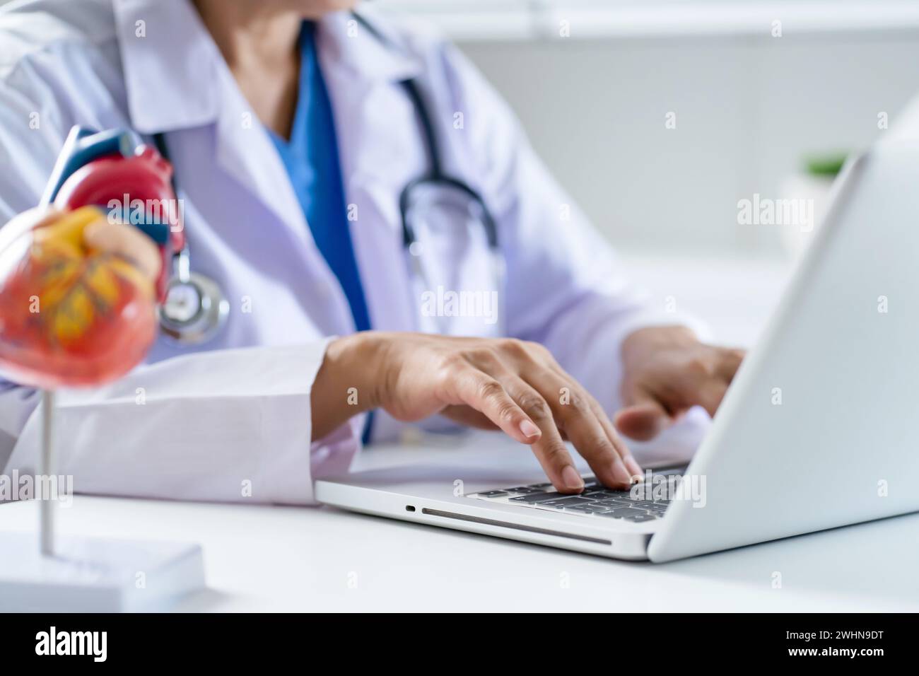 Doctor consult patient on laptop with anatomical model of human heart ...