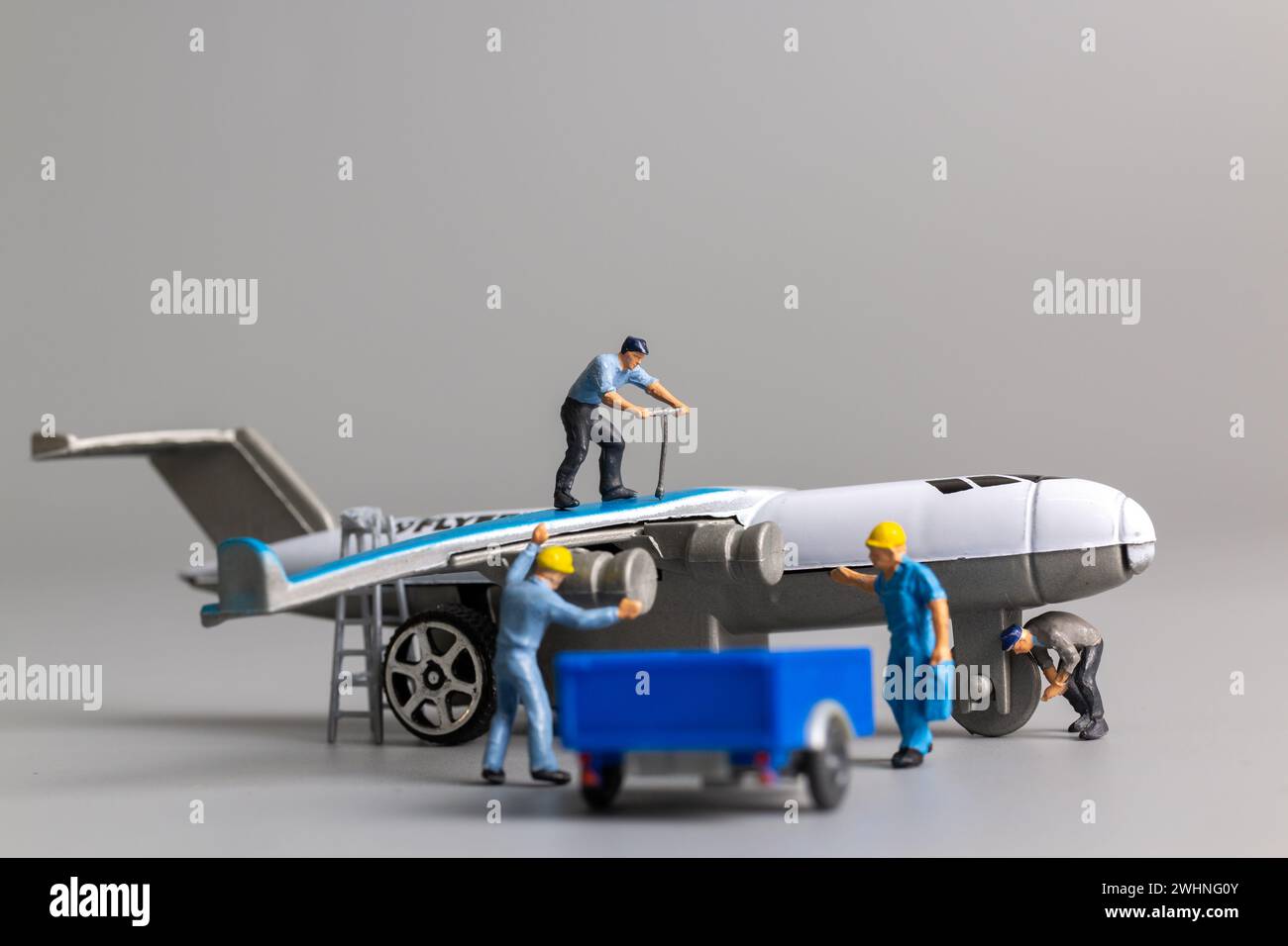 Miniature worker team checking and repairing airplane on gray ...