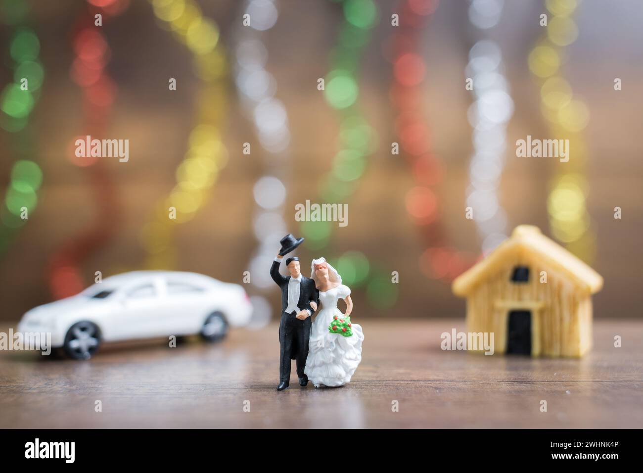 Miniature people bride and groom on wooden floor with colorful bokeh ...