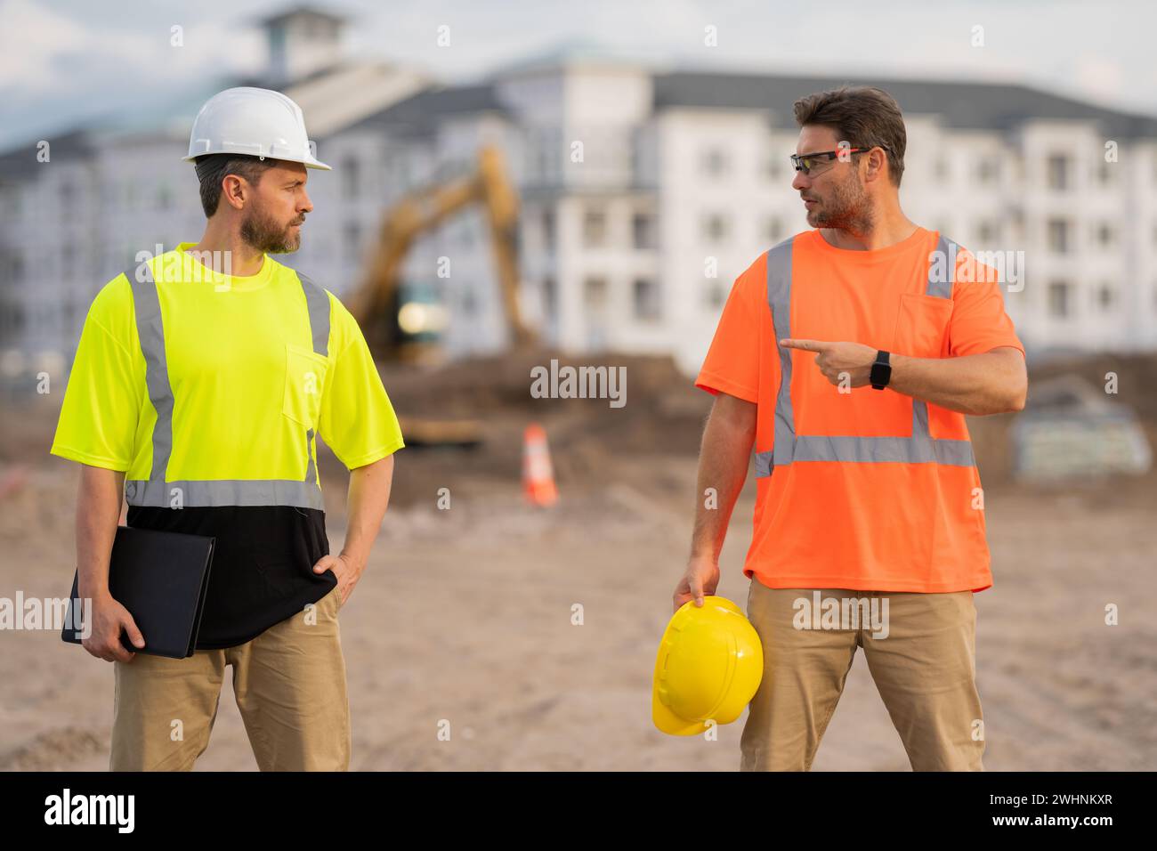 Two construction workers with hardhat helmet on construction site ...