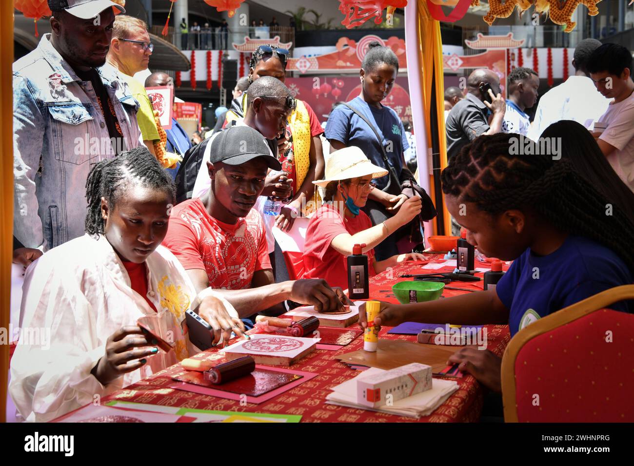 Nairobi, Kenya. 10th Feb, 2024. People try Chinese calligraphy and wood ...