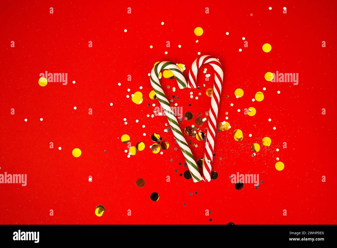 Two sweet candies cane form a heart shape. Bright red background with ...