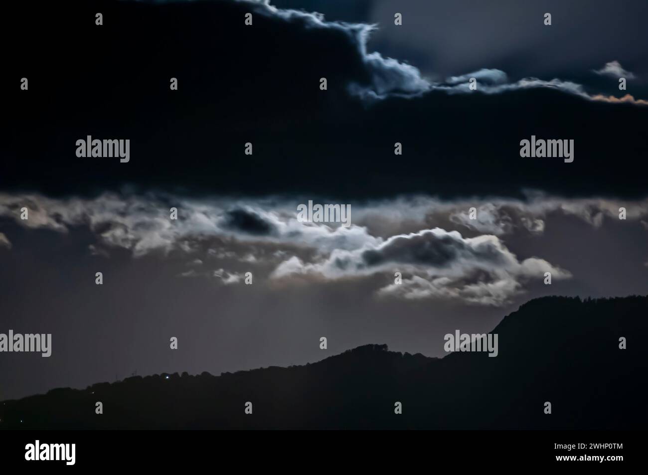 Full moon covered by clouds with profile of mountains Stock Photo - Alamy