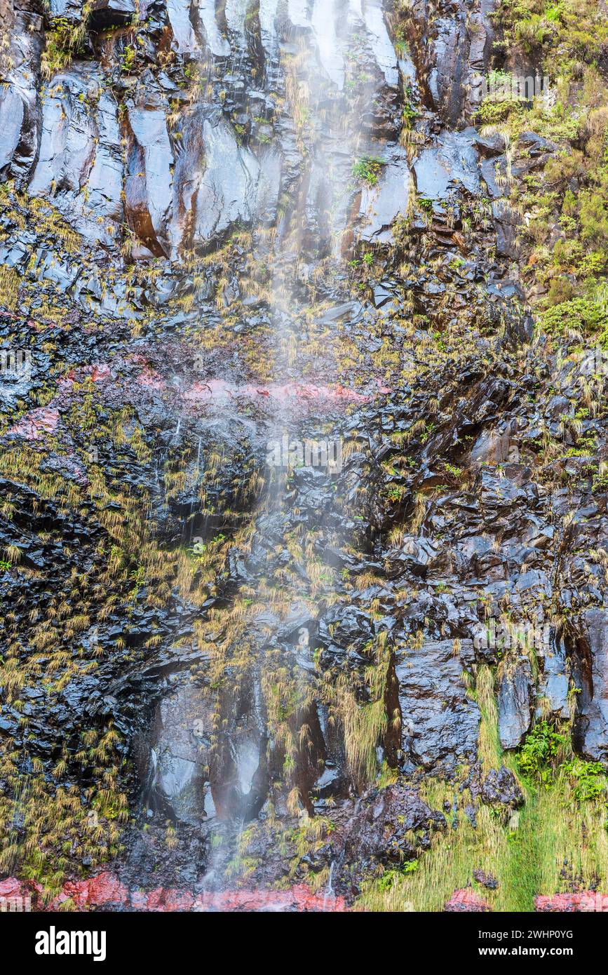 Falling waterfall on steep slope coveredy by grass and srones above ...