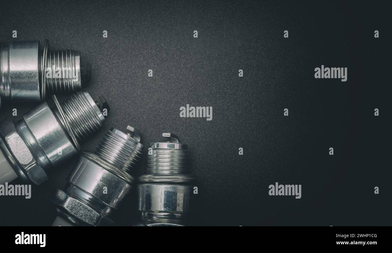 Four spark plugs arranged in a semicircle on a gray gradient background ...