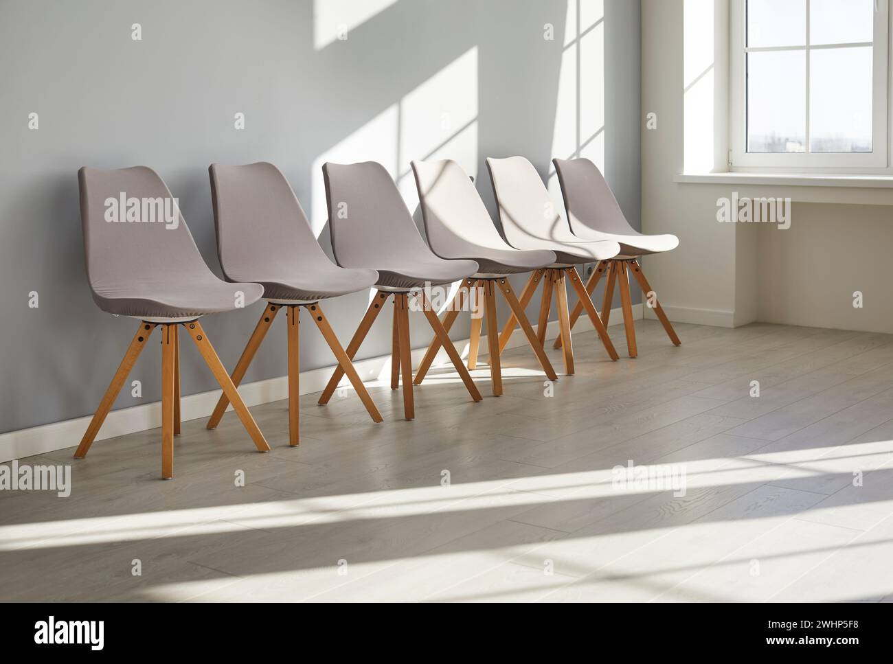 Chairs standing in a row by the wall in an empty office corridor or ...