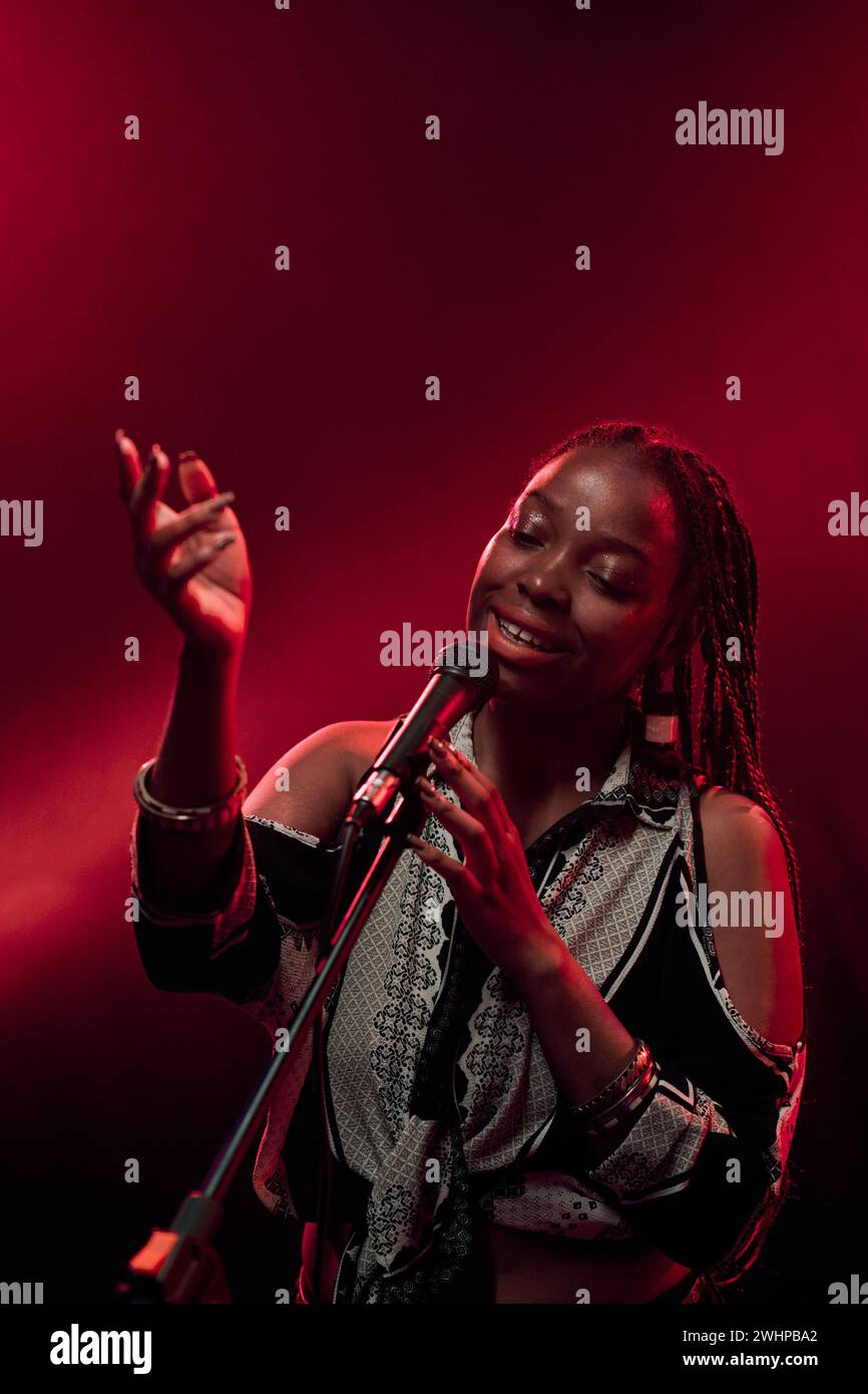 Vertical portrait of young African American woman singing into ...