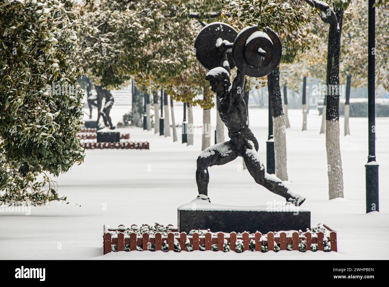 A statue of a weightlifter on display in a snow-covered park in Wuhan ...