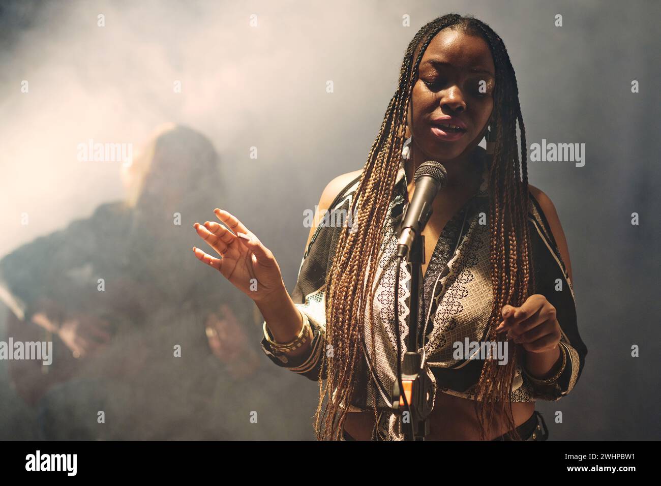 Waist up portrait of young Black woman musician singing on stage with ...