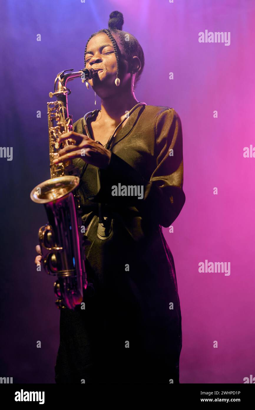 Vertical portrait of talented African American woman playing saxophone ...