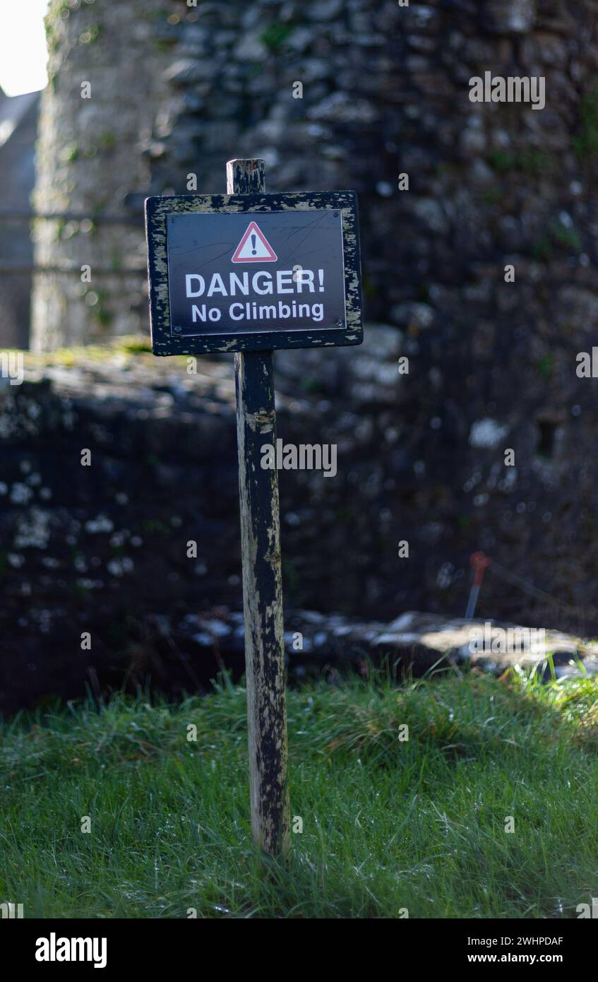 Black, danger sign in front of an old, stone city wall around a castle ...