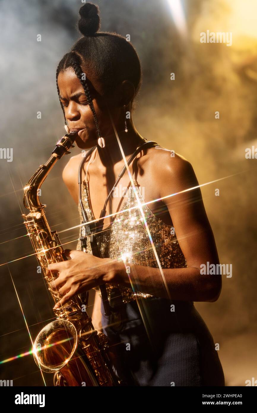 Vertical portrait of talented young woman playing saxophone during jazz ...