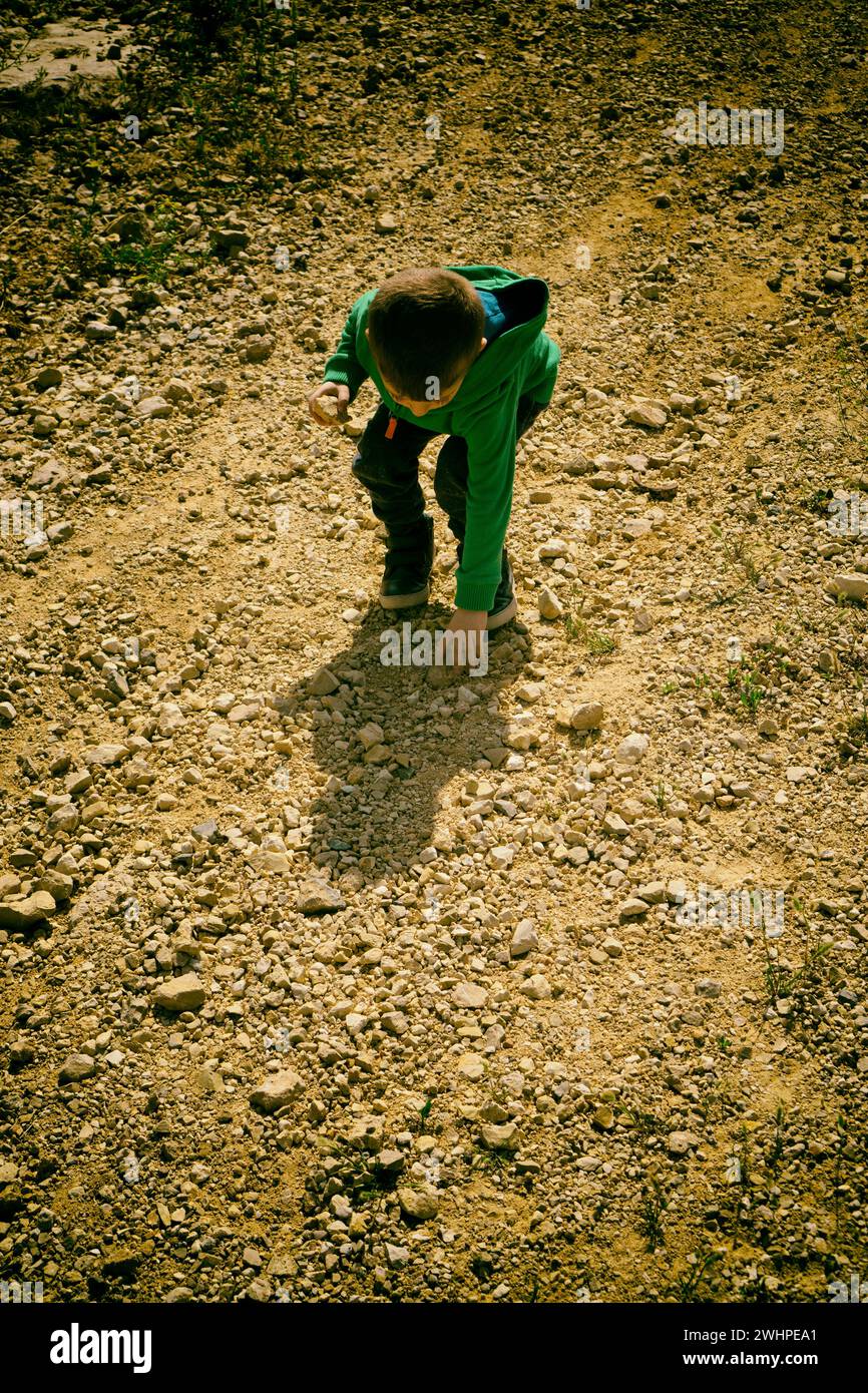 Little boy picking stones from the ground Stock Photo - Alamy