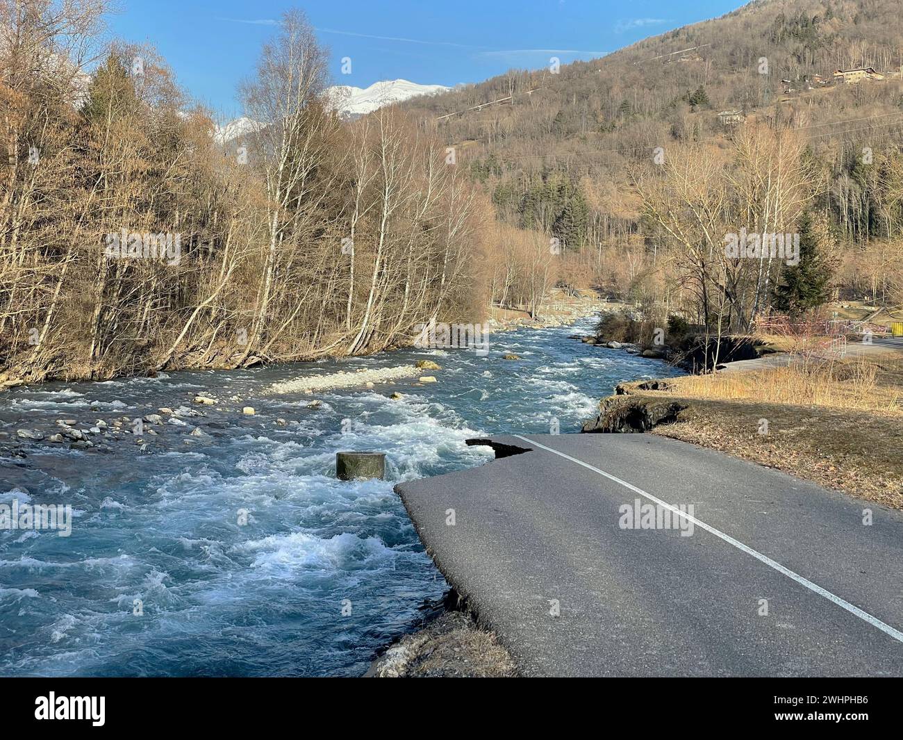 biking road at the edge of a river flowing in an alpine valley destroy ...