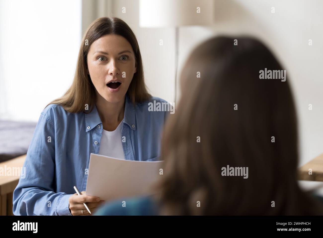 Shocked entrepreneur woman holding paper document, staring at colleague ...