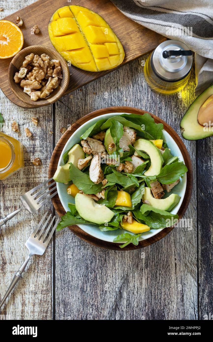 Healthy diet salad with chicken, grill arugula, mango, avocado and vinaigrette dressing on a ...